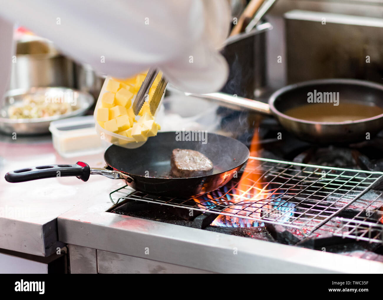 Chef cooking with flame in a frying pan on a kitchen stove Stock Photo ...