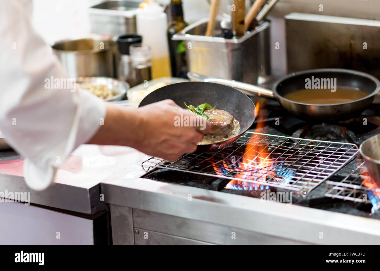 Chef cooking with flame in a frying pan on a kitchen stove Stock Photo ...