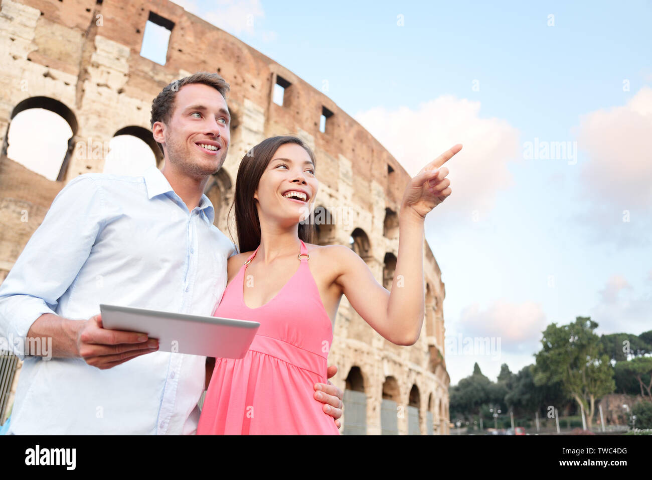Happy travel couple with tablet by Coliseum, Rome, Italy. Smiling young ...