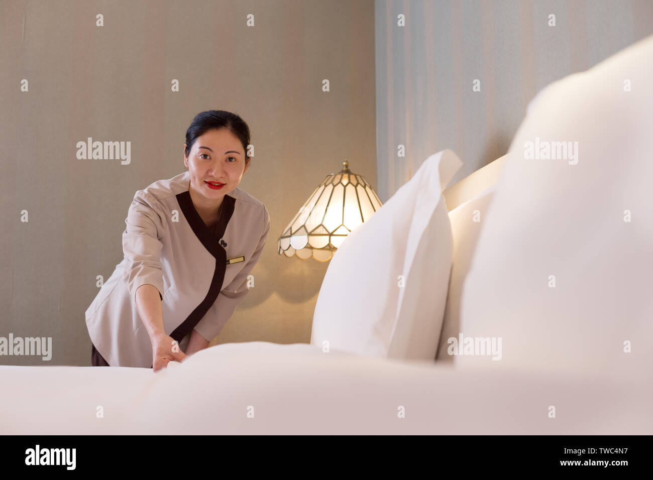 young chinese woman housekeeper makes bed in modern hotel Stock Photo ...