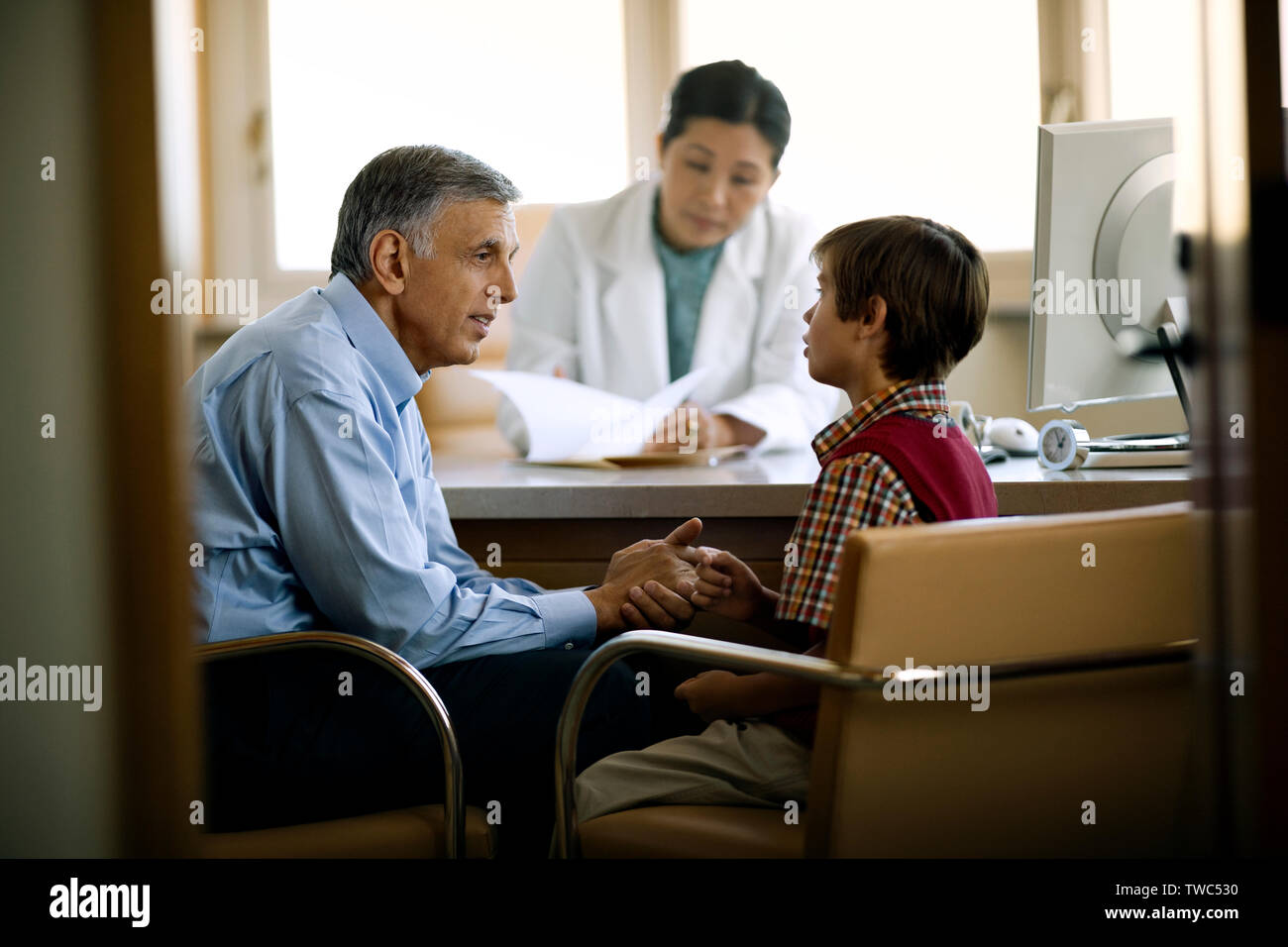 Mid adult doctor consulting with a young boy and his father Stock Photo ...