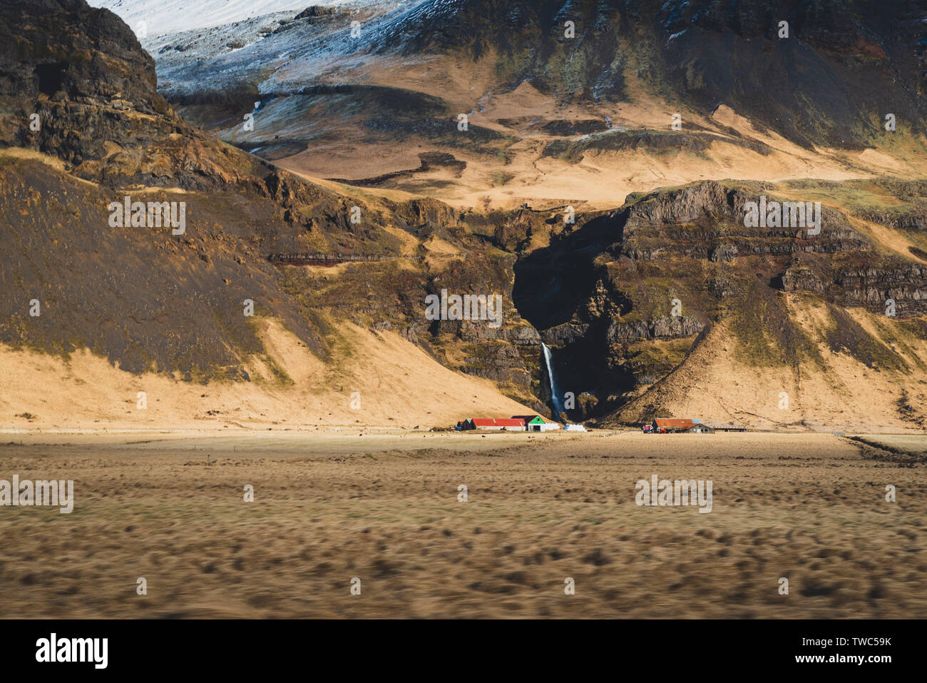 Icelandic landscape with a waterfall and farms, shot through the window ...