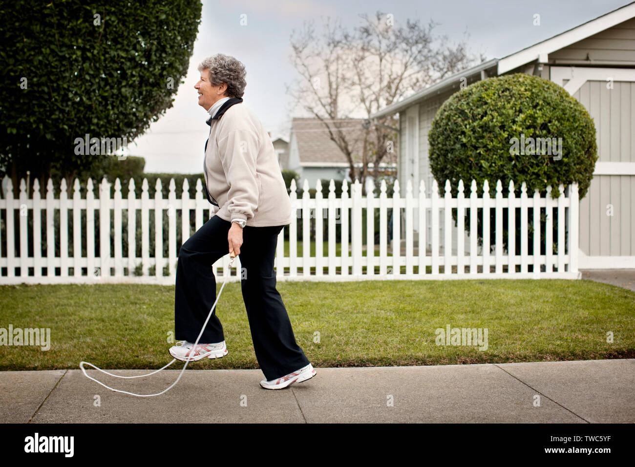 A senior woman playing jump rope on the sidewalk Stock Photo - Alamy