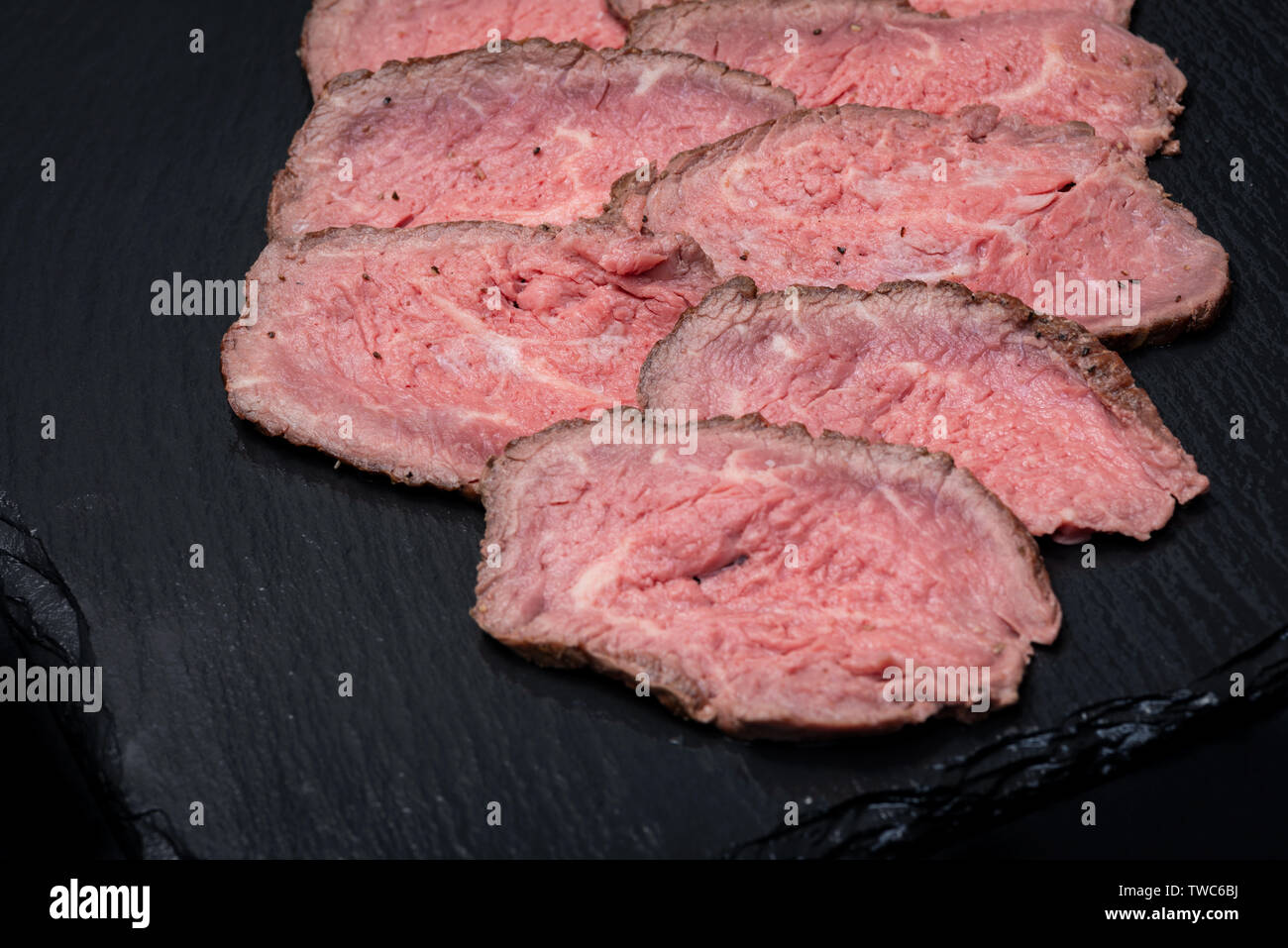 Sliced Grass Fed Juicy Corn Roast Beef on black natural stone ...