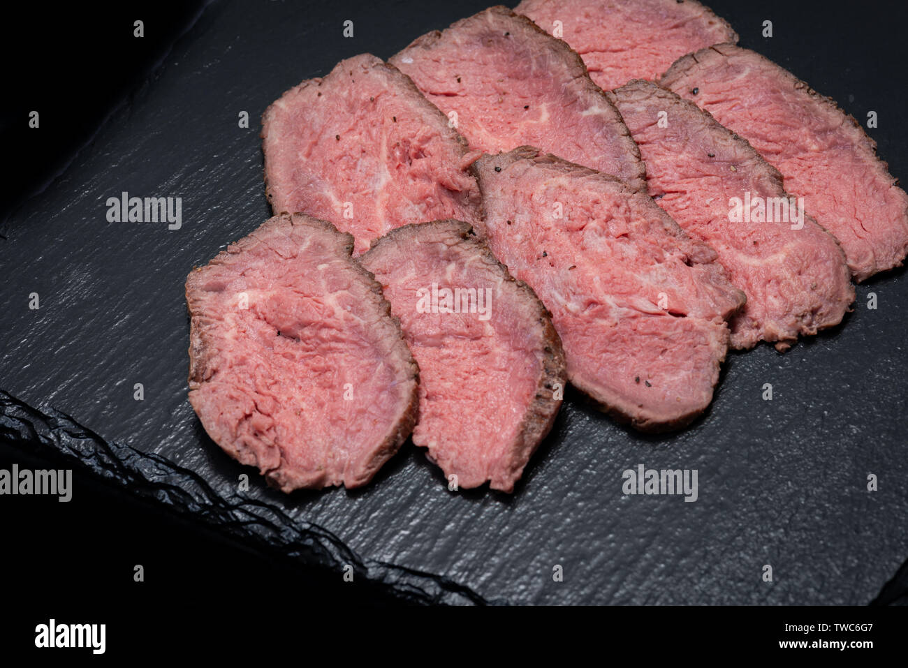 Sliced Grass Fed Juicy Corn Roast Beef on black natural stone ...