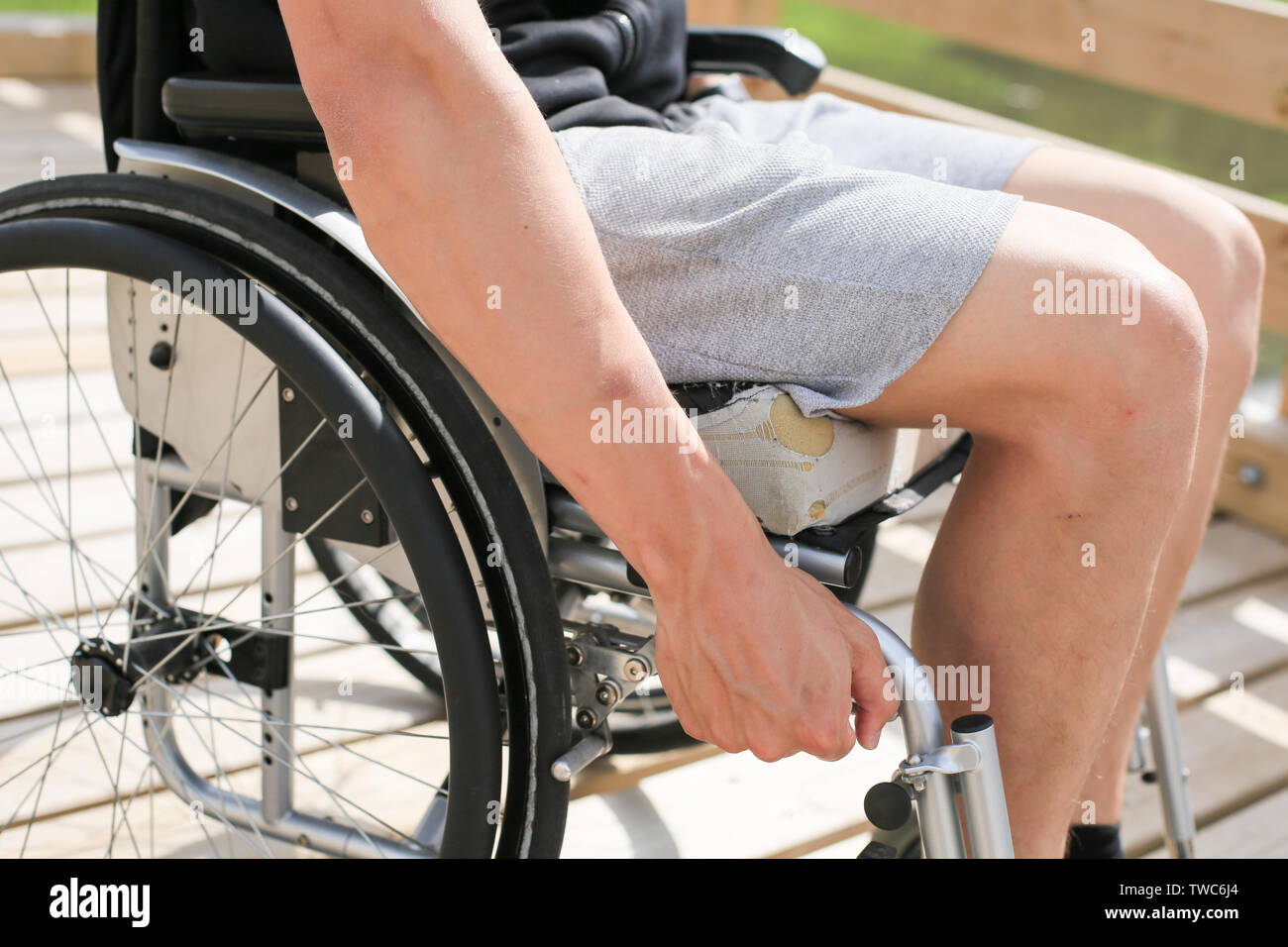 Disabled young athletic man on a wheelchair holding and turning wheels ...