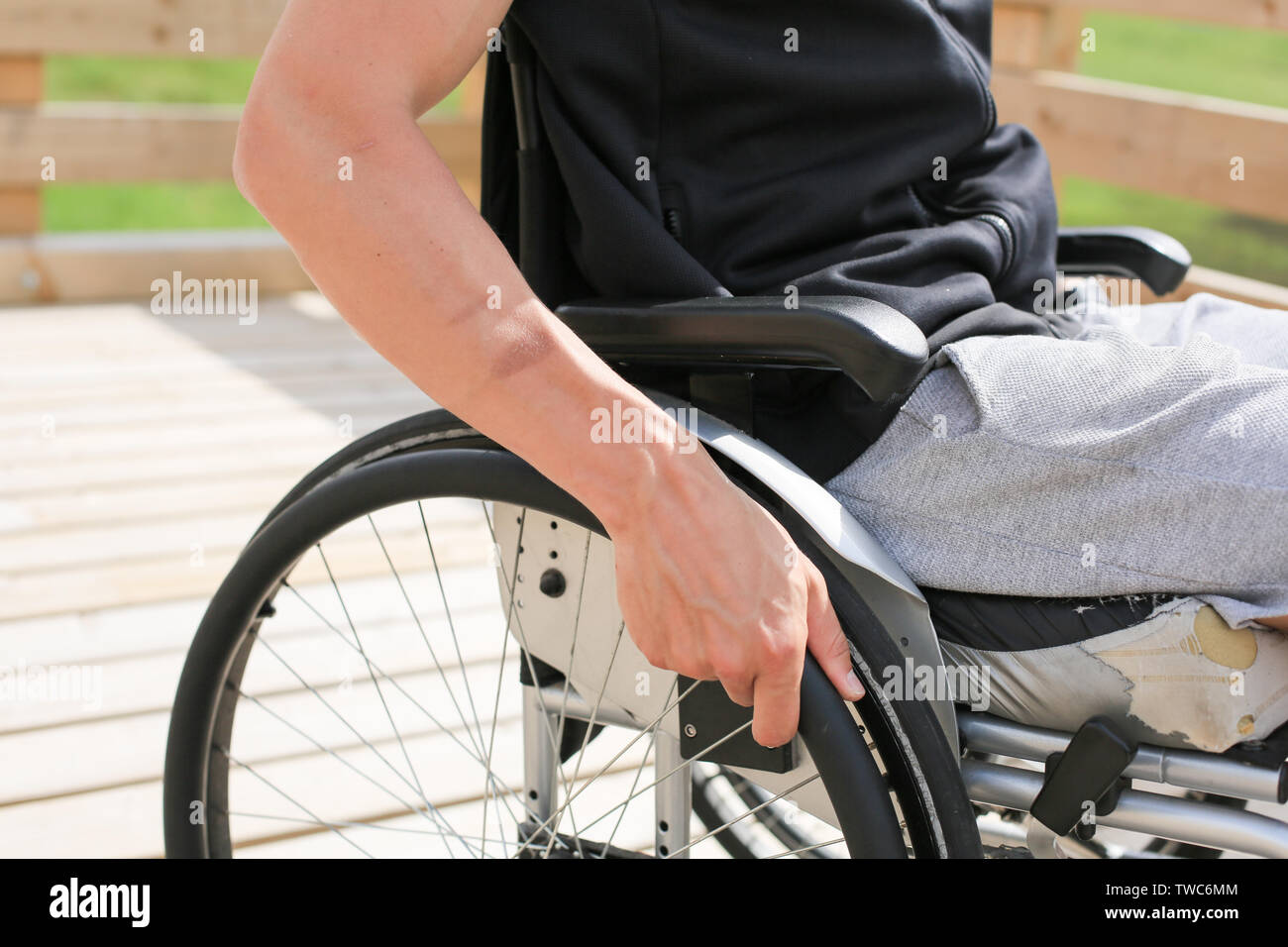 Disabled young athletic man on a wheelchair holding and turning wheels ...