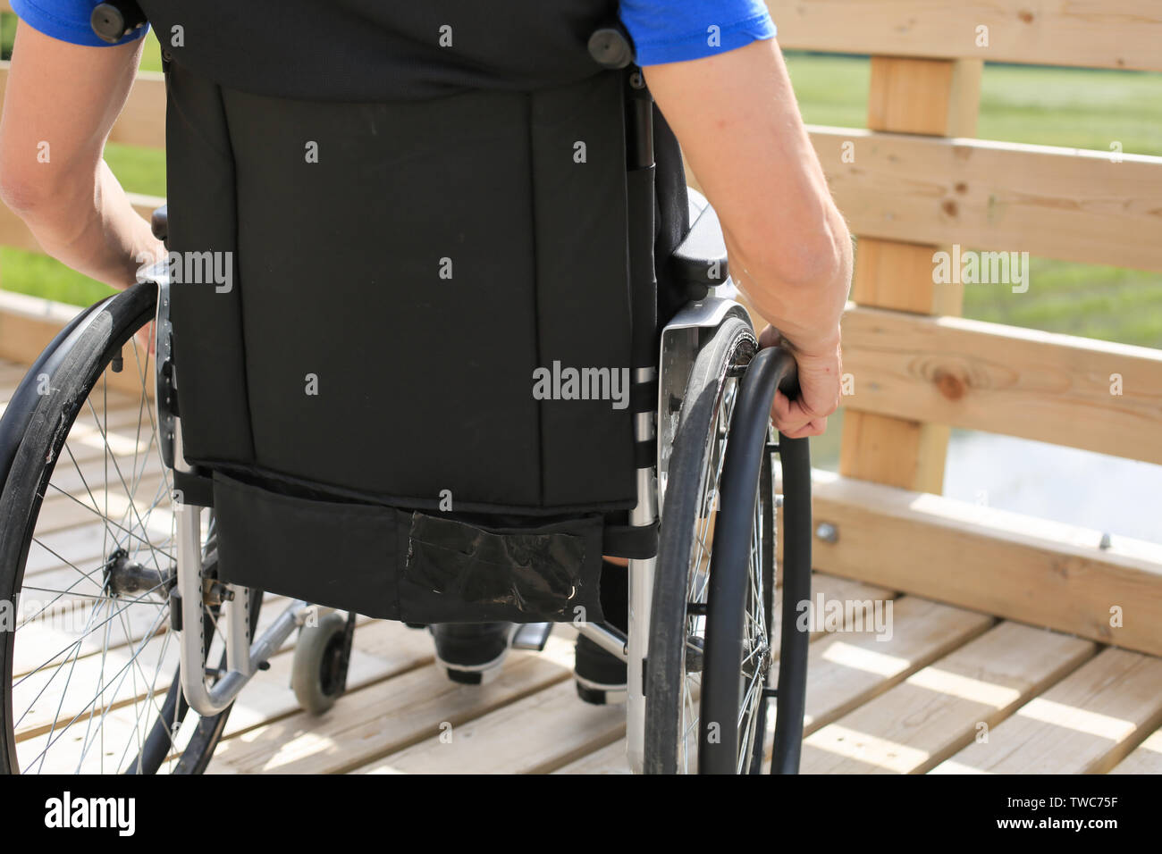 Disabled young man on a wheelchair holding and turning wheels with hand ...