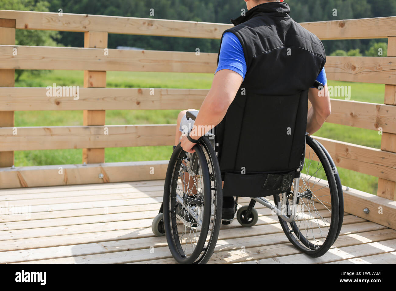 Disabled young man on a wheelchair holding and turning wheels with hand ...