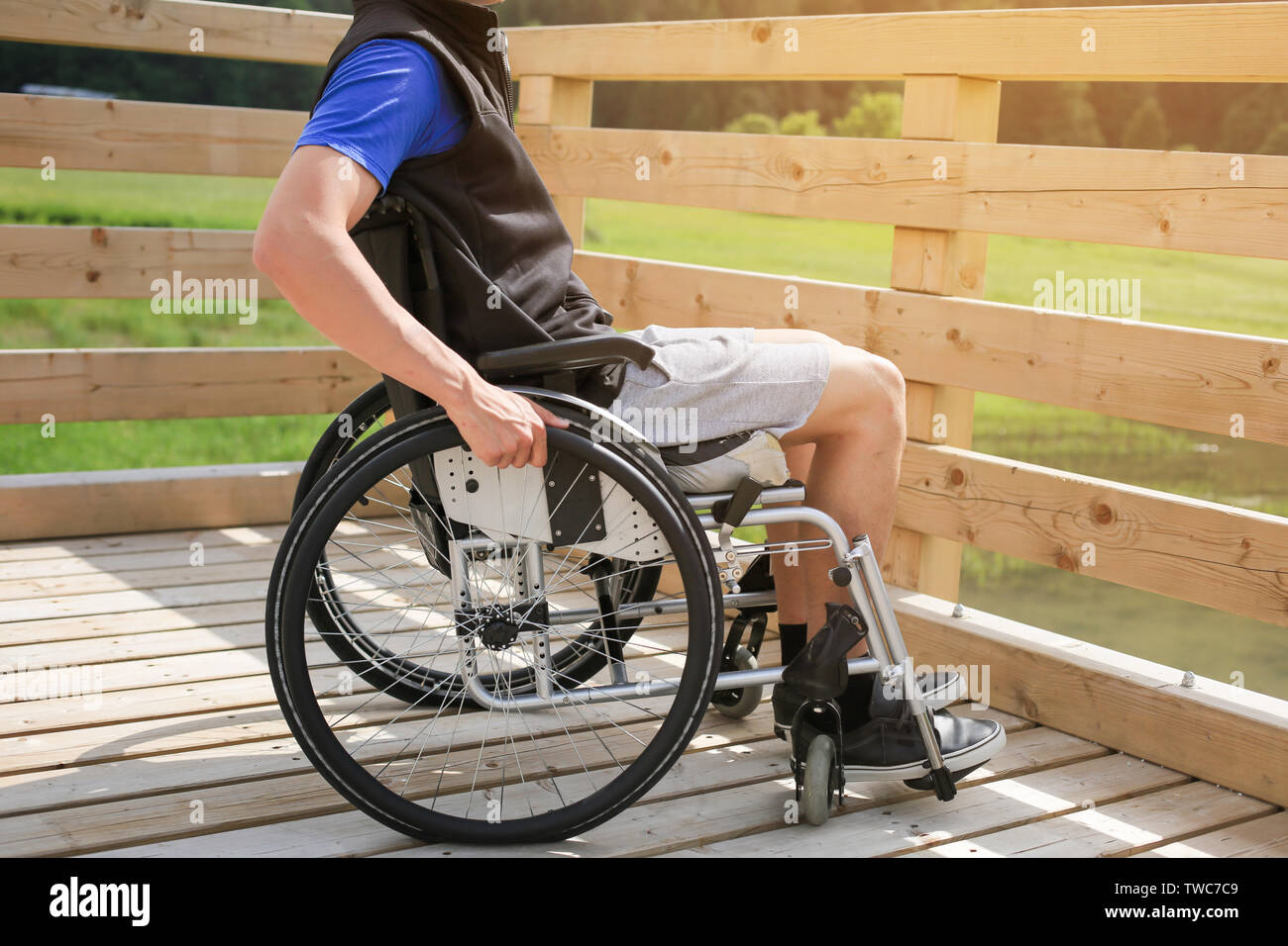 Disabled young man on a wheelchair holding and turning wheels with hand ...