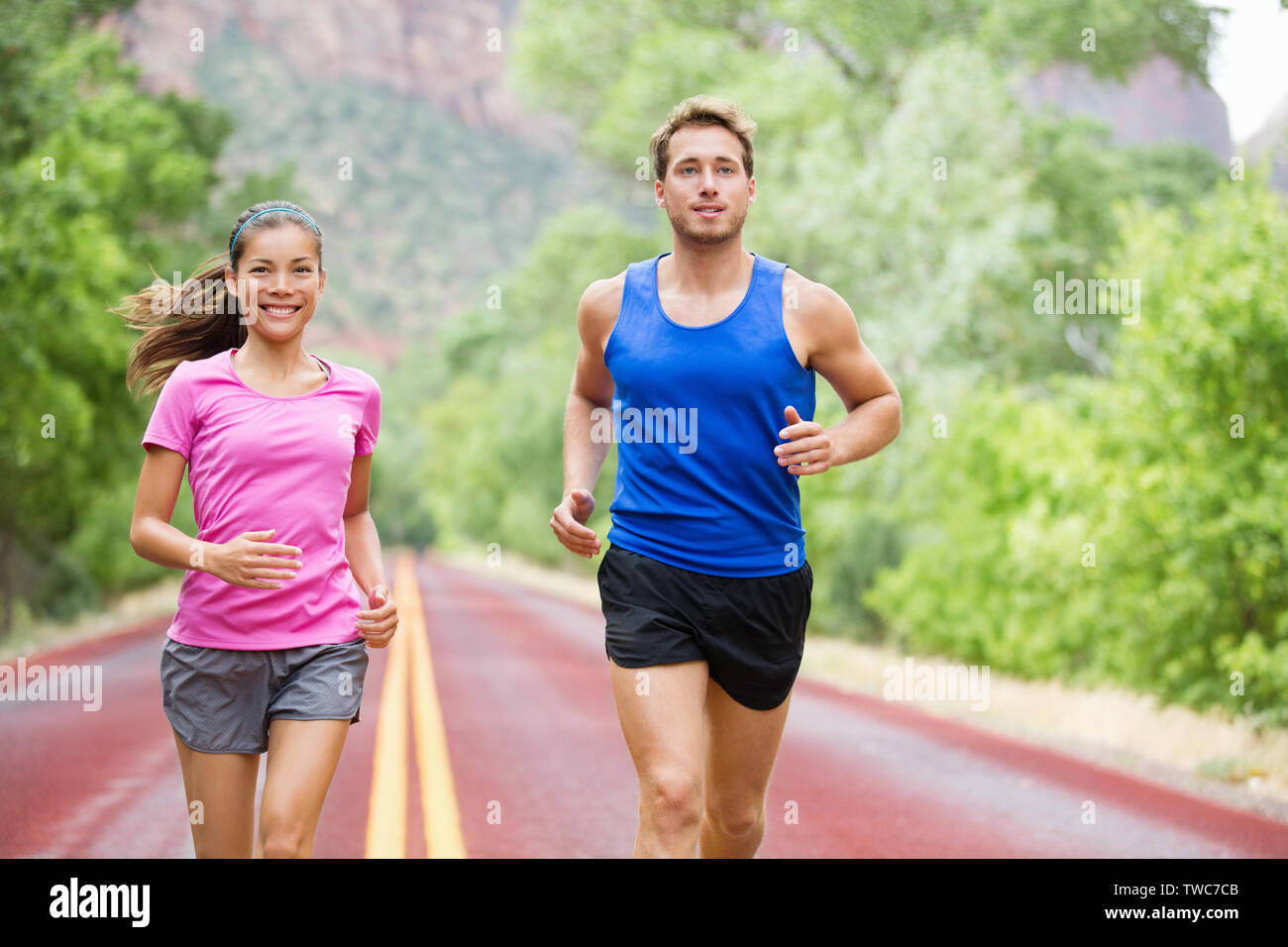 Runners couple in jogging exercise outside on road in beautiful nature ...