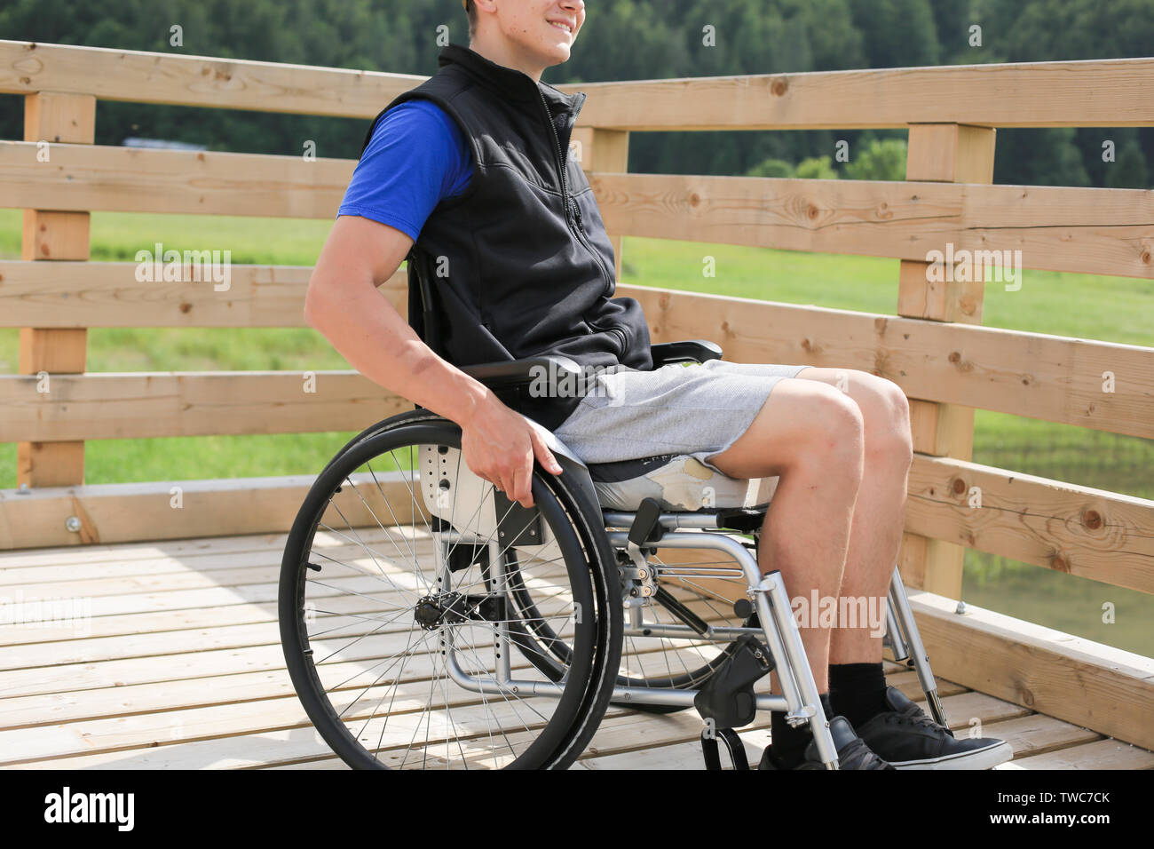 Disabled young man on a wheelchair holding and turning wheels with hand ...