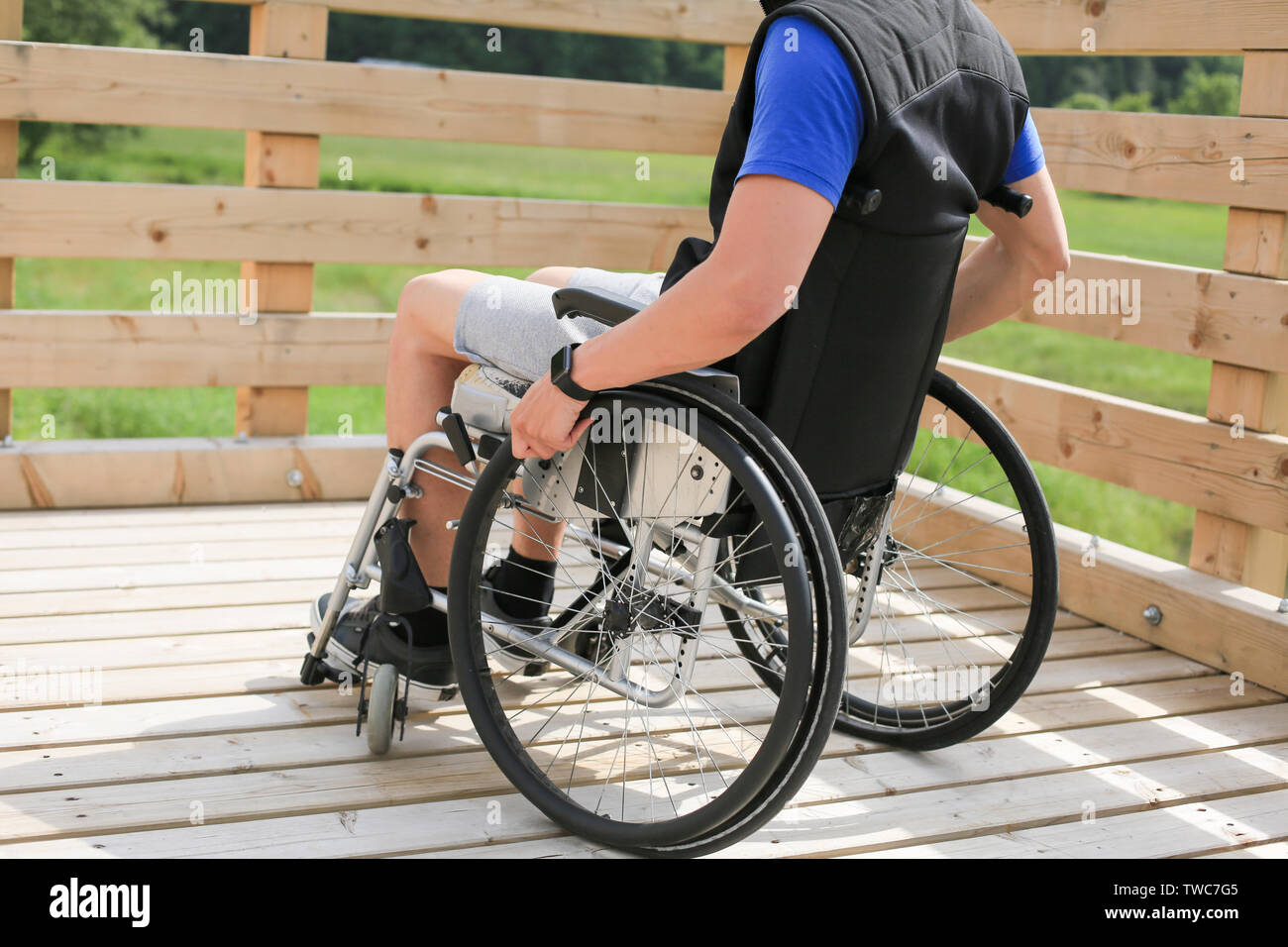 Disabled young man on a wheelchair holding and turning wheels with hand ...