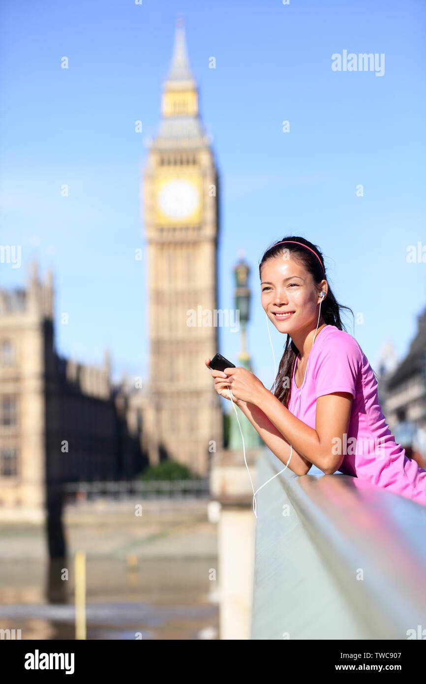 London woman runner listening to music on smartphone near Big Ben ...