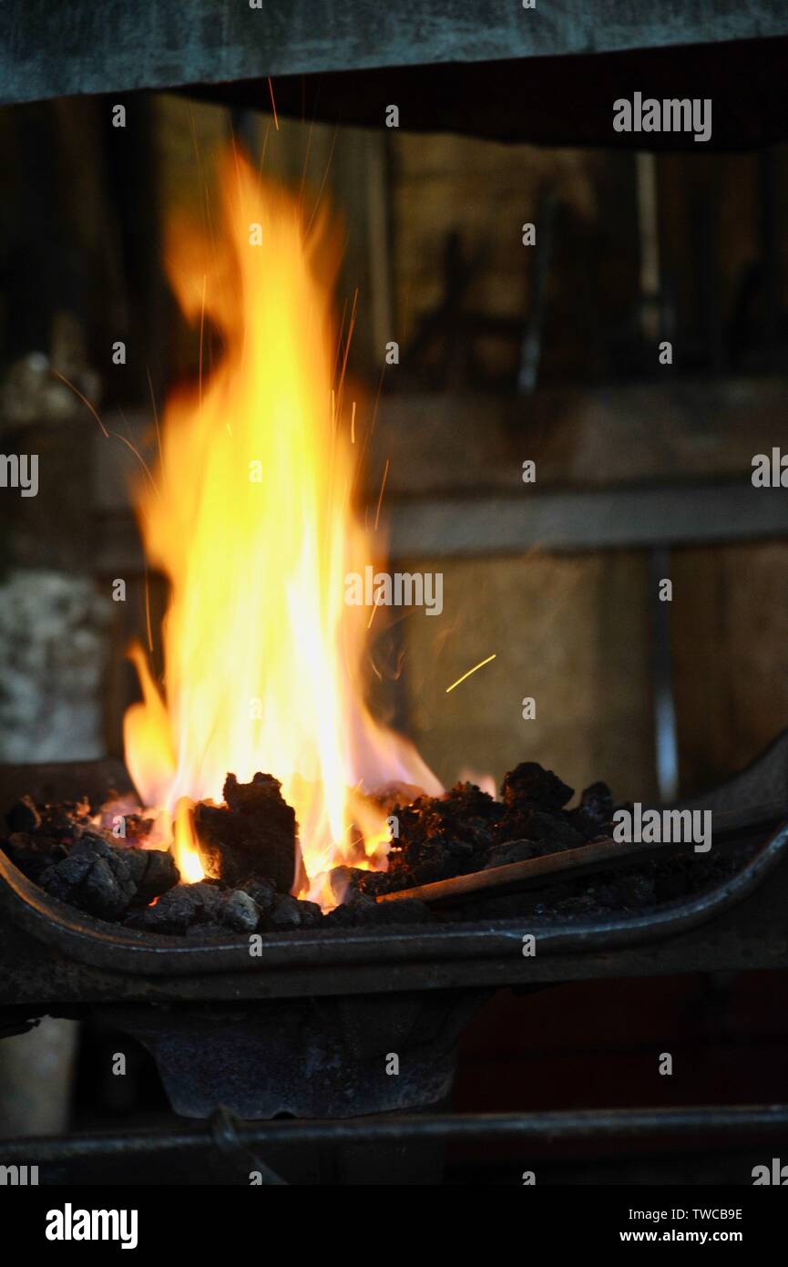 Close up of flames with male blacksmith forge at work making metal ...