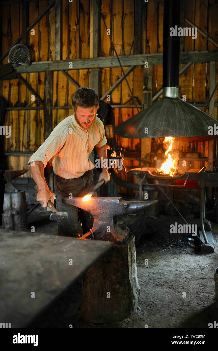 Male blacksmith forging metal, making metal shapes in his blacksmith ...