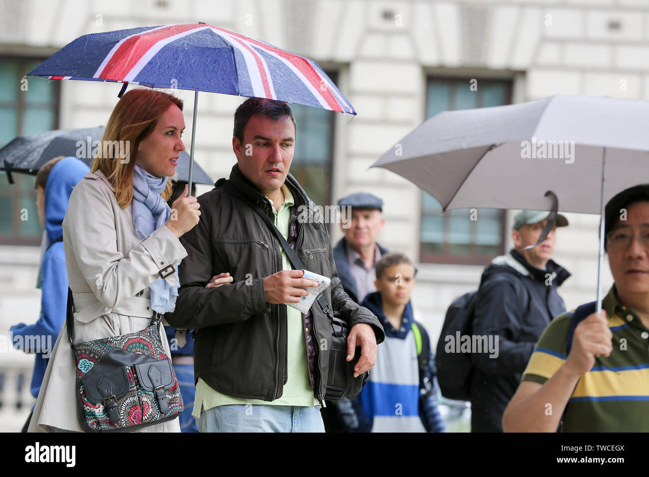 A woman shelters from the rain beneath an Union Jack umbrella during ...