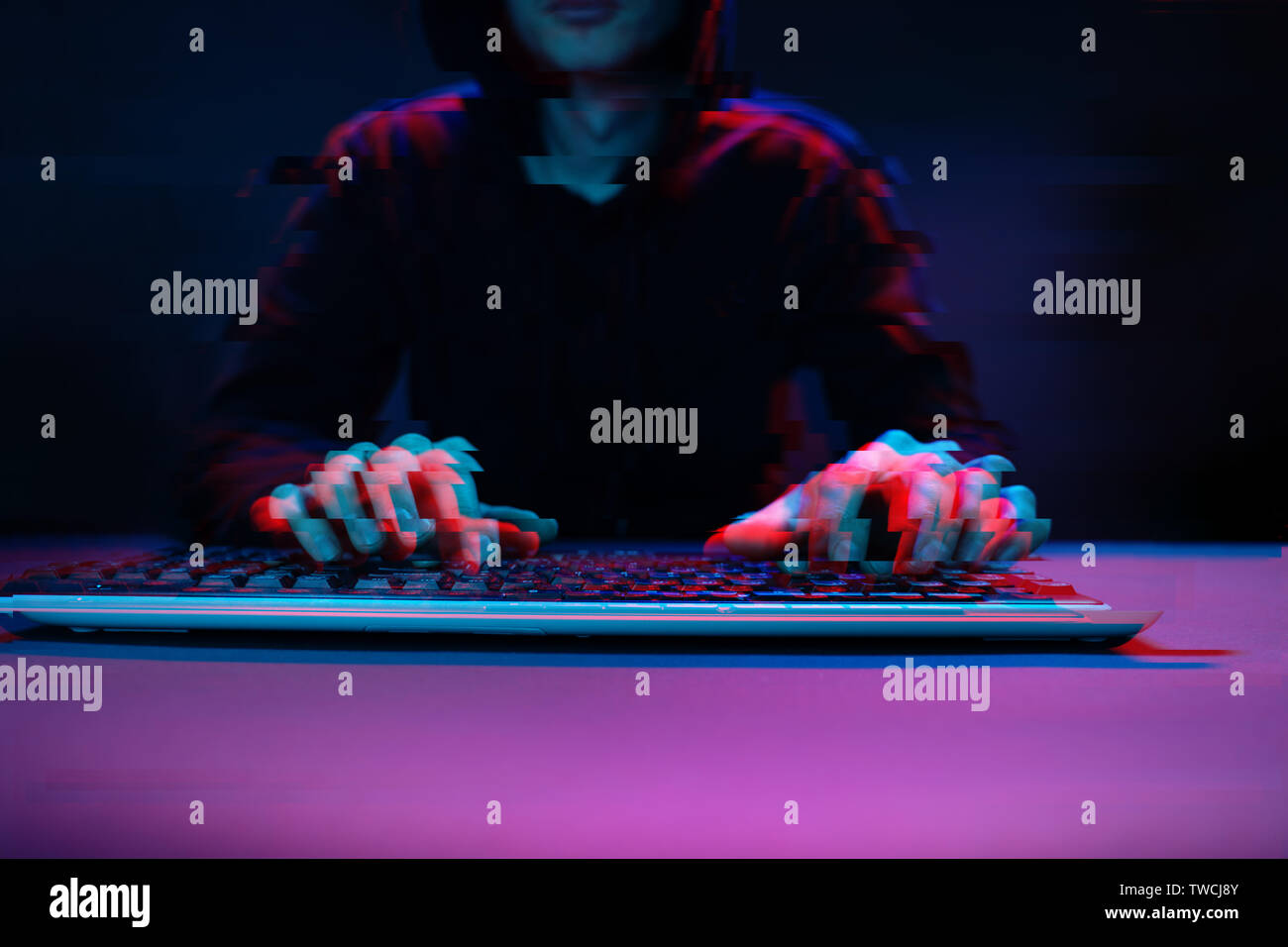 Hacker in the hood working with computer typing text in dark room ...