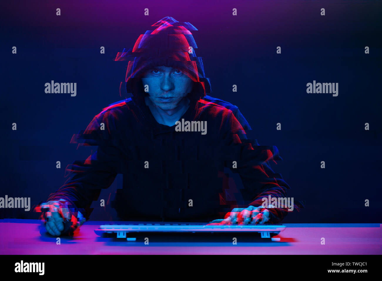 Hacker in the hood working with computer typing text in dark room. Image with glitch effect ...