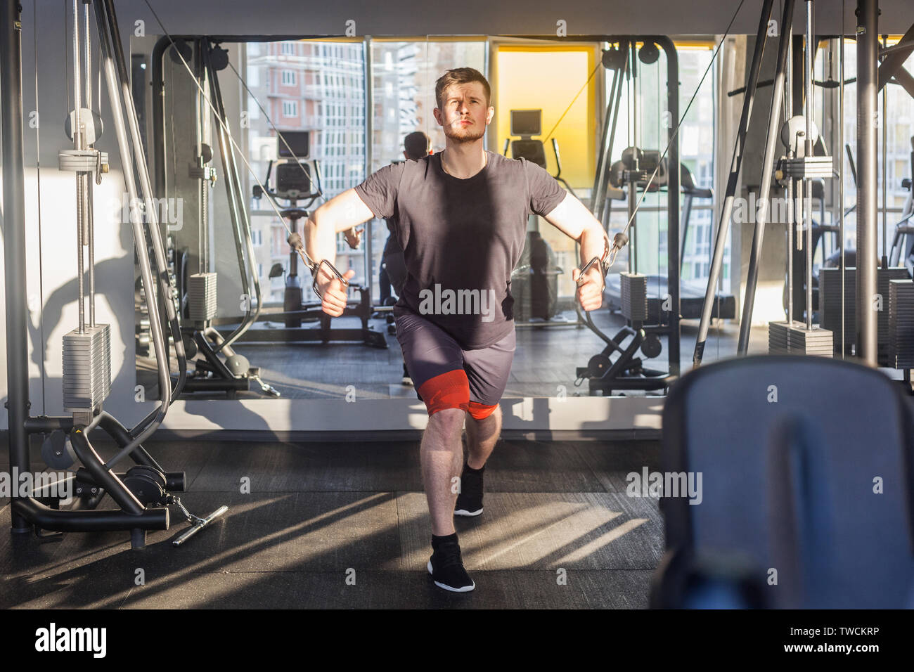 Young adult confident crossfit man standing and doing trx exercises in ...