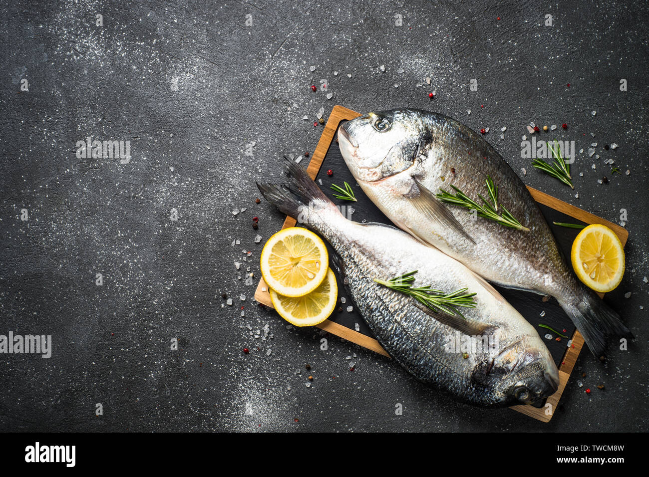 Raw dorado fish on black background Stock Photo - Alamy
