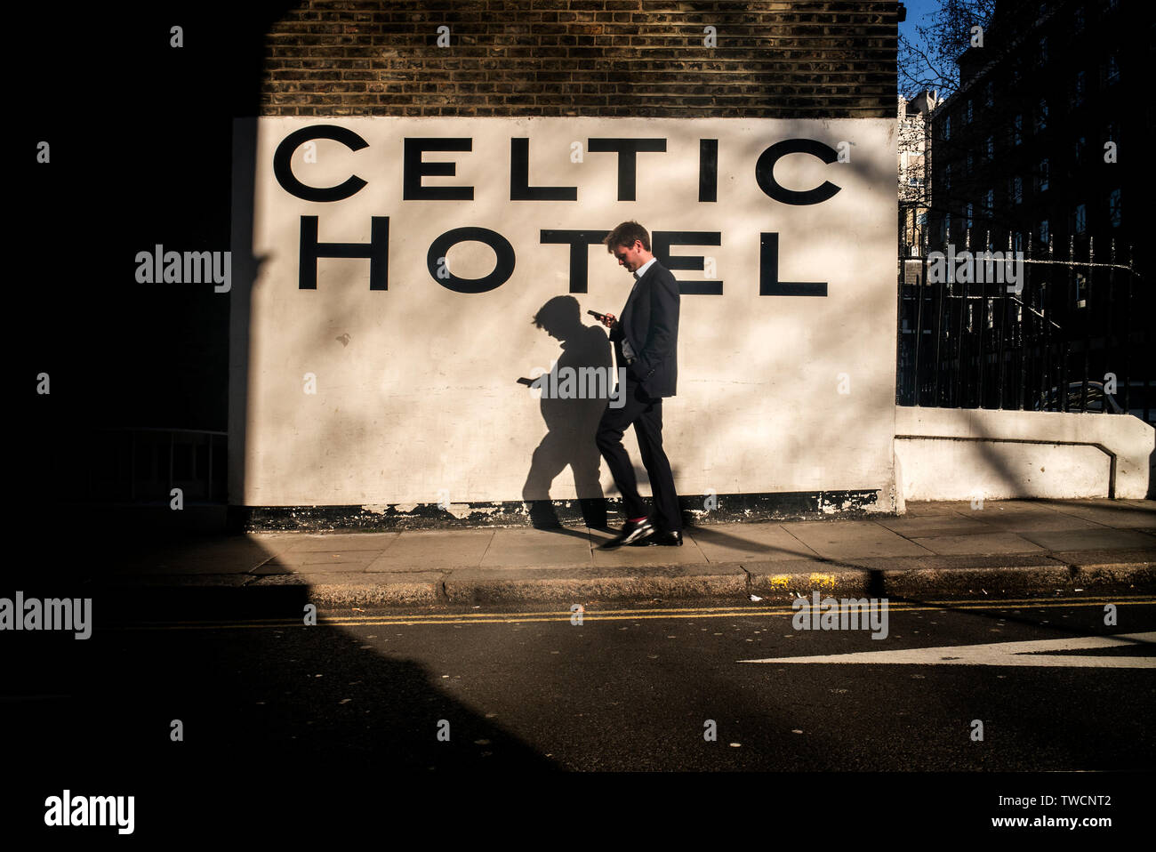 shadow silhouette of man talking on the phone projected on white wall ...