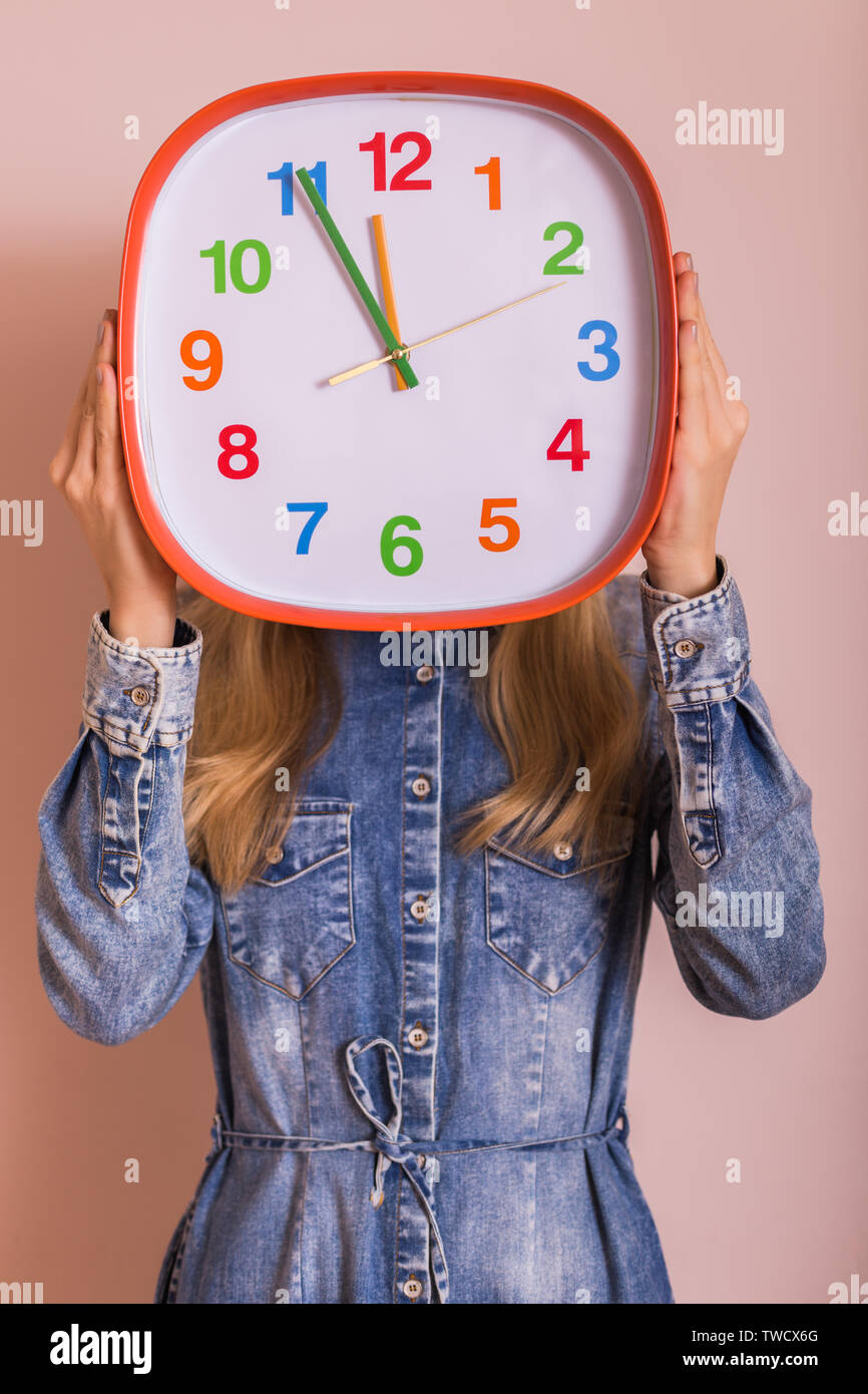 Woman holding clock while standing in front of wall Stock Photo - Alamy