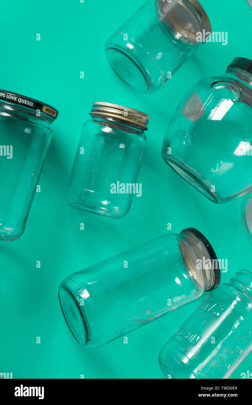 Transparent glass jars with lids isolated on teal green background, top ...