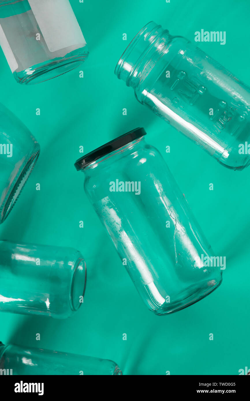 Transparent glass jars with lids isolated on teal green background, top ...