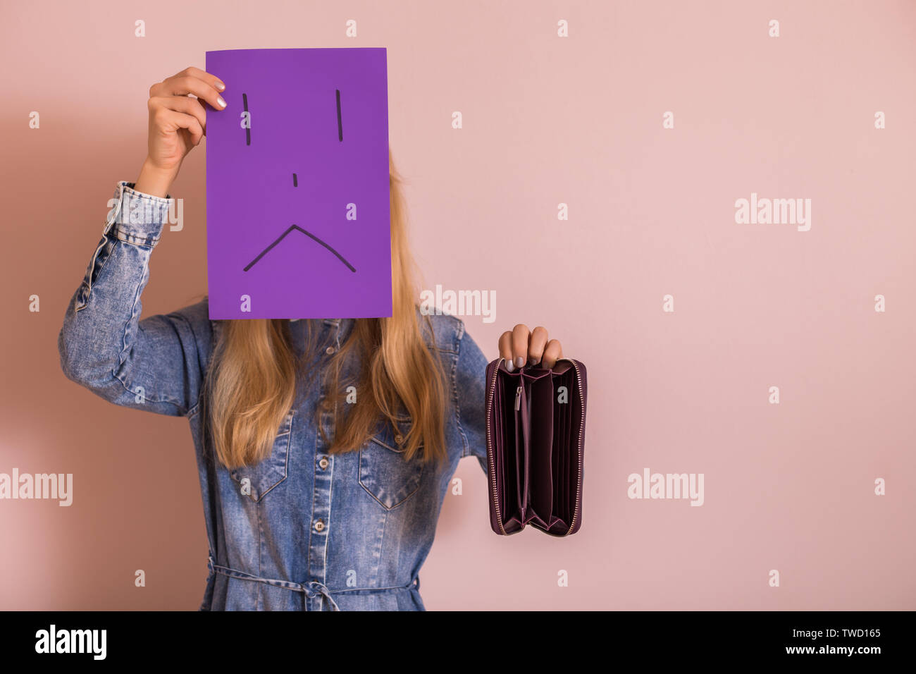 Woman holding empty wallet and sad face on paper while standing in ...