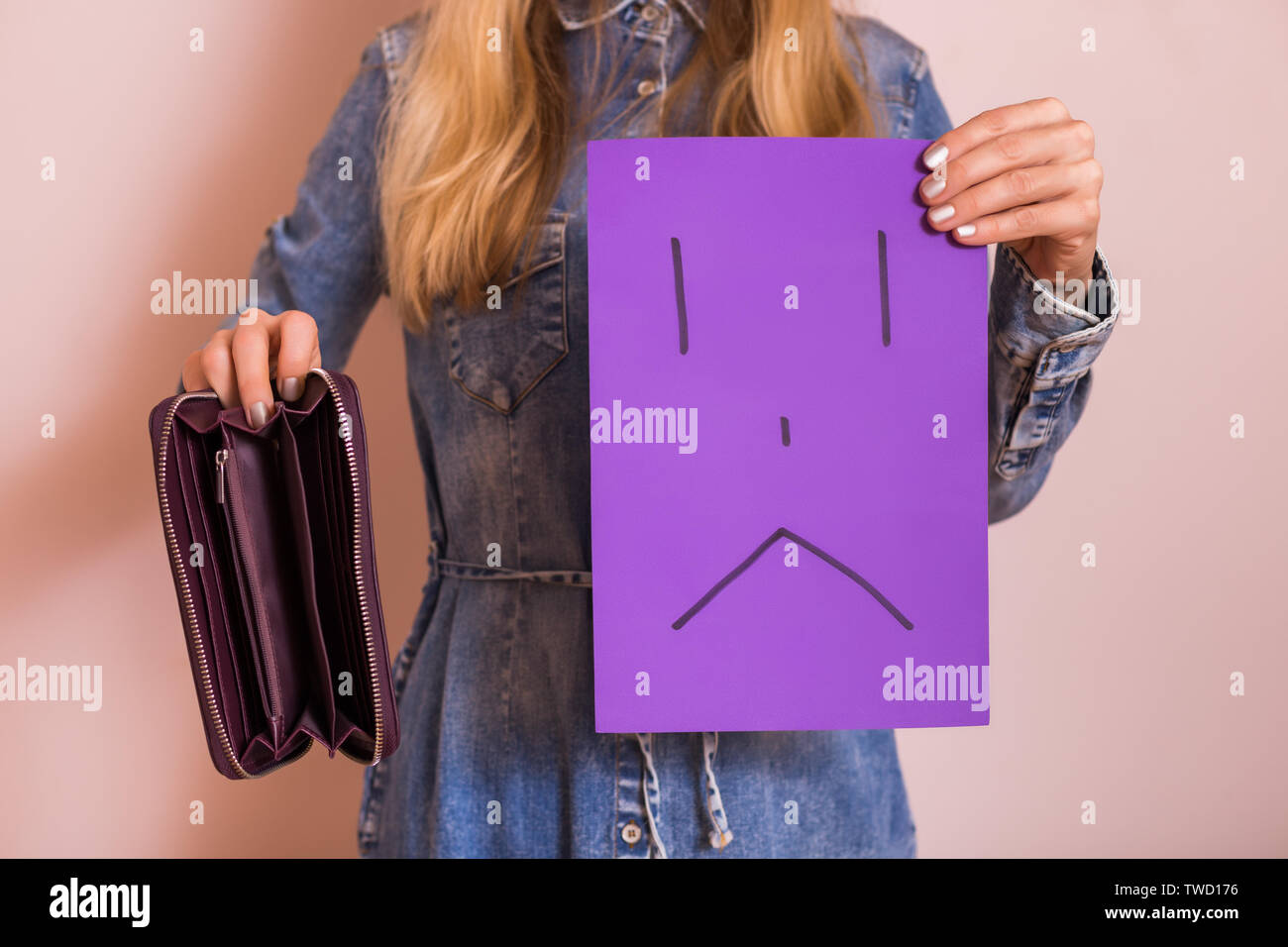 Woman holding empty wallet and sad face on paper while standing in ...