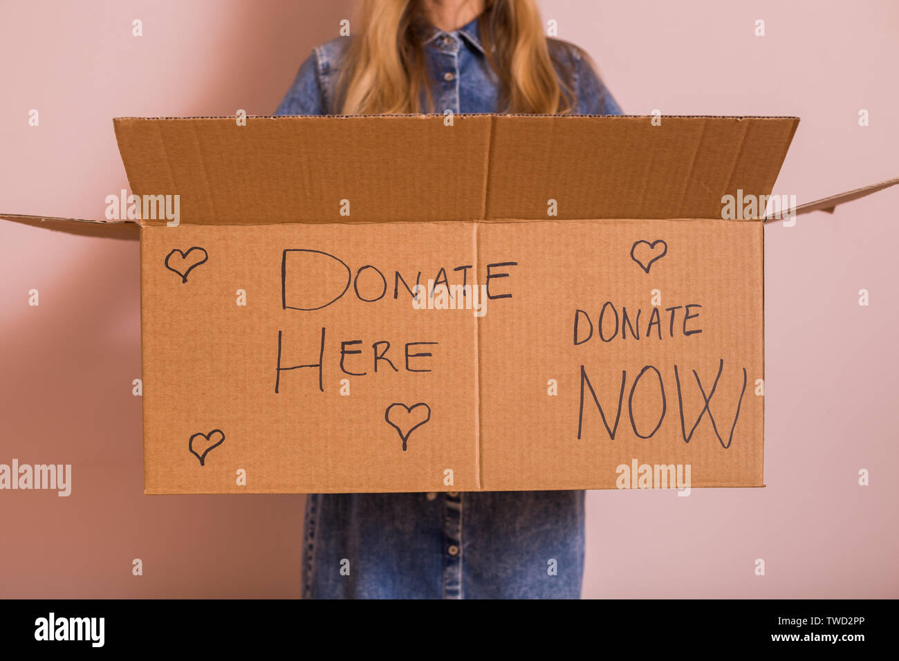 Woman holding donation box while standing in front of wall Stock Photo ...