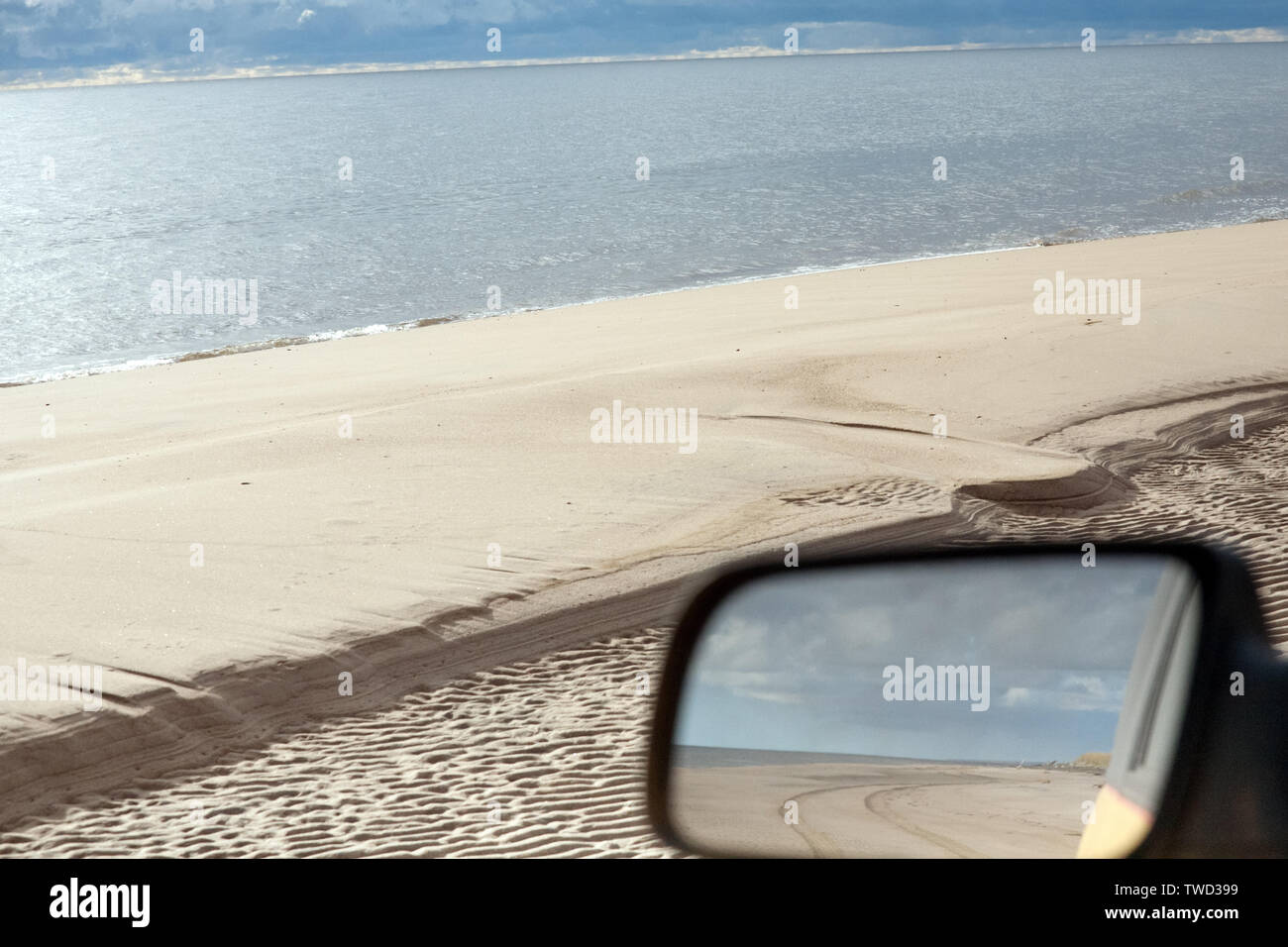 rearview mirror of car on sandy sea beach with off road track closeup ...
