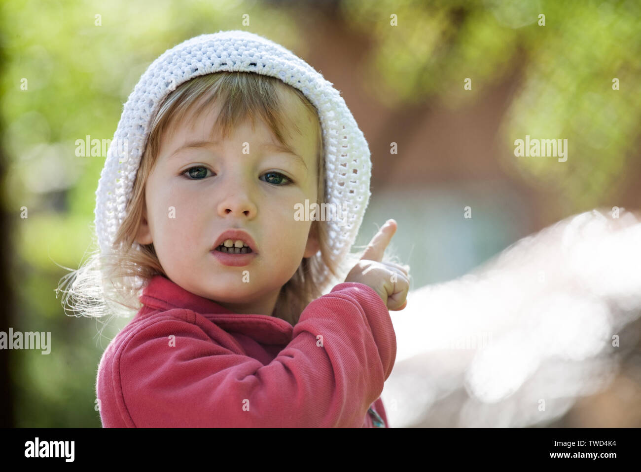 little child caucasian girl in white hat pointing with forefinger ...