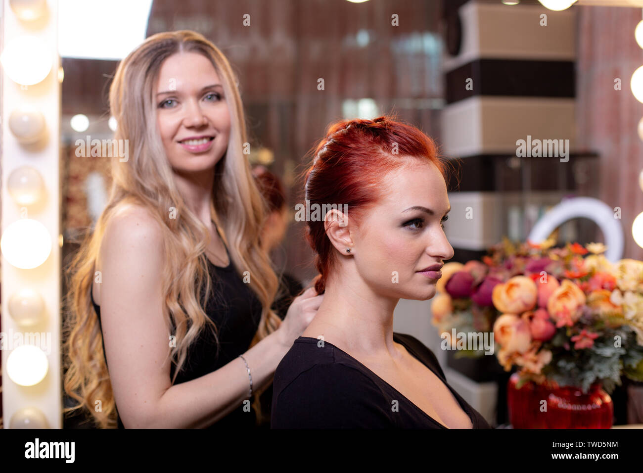 Beautiful, red-haired girl with long hair, hairdresser weaves a French ...
