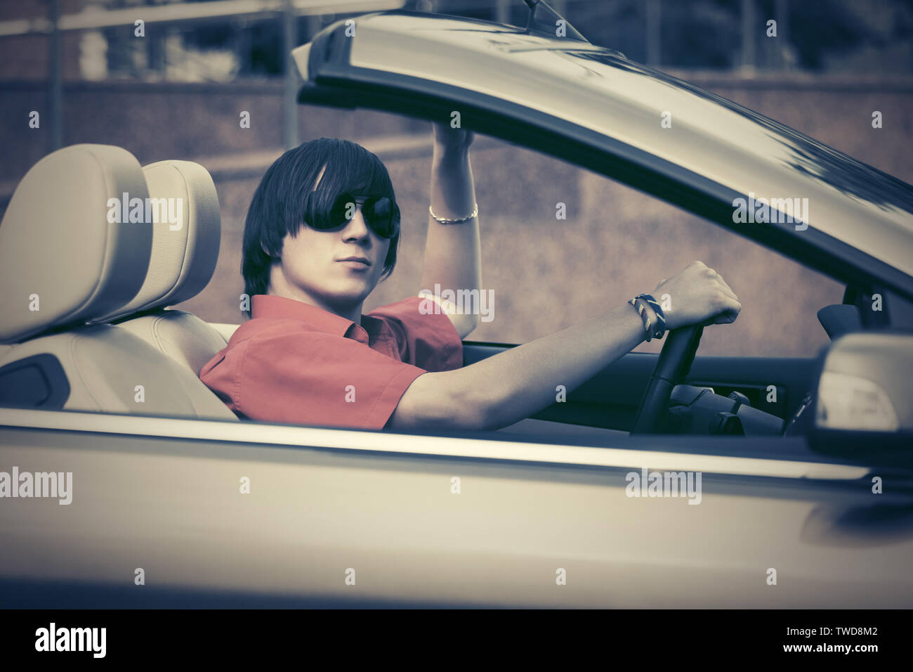 Young handsome man in red shirt and sunglasses driving convertible car ...