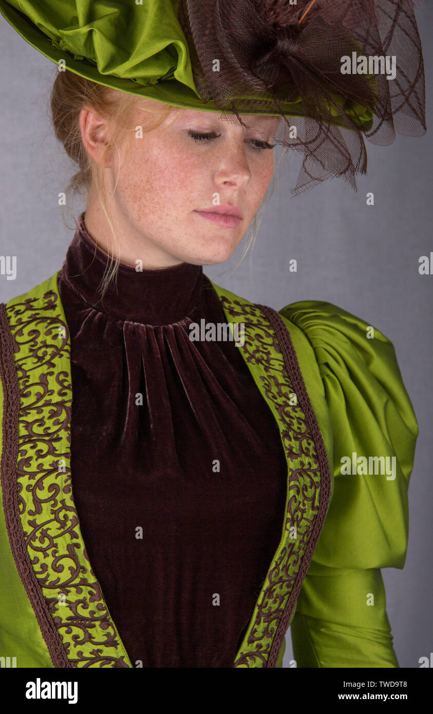 Late Victorian woman wearing a green silk ensemble and a large hat ...