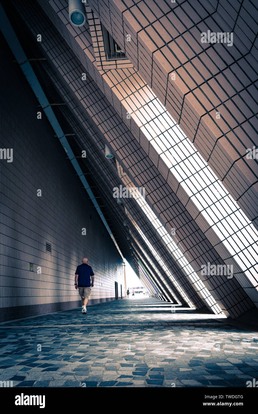 Lonely old man walking alone through the mottled streets of light and ...