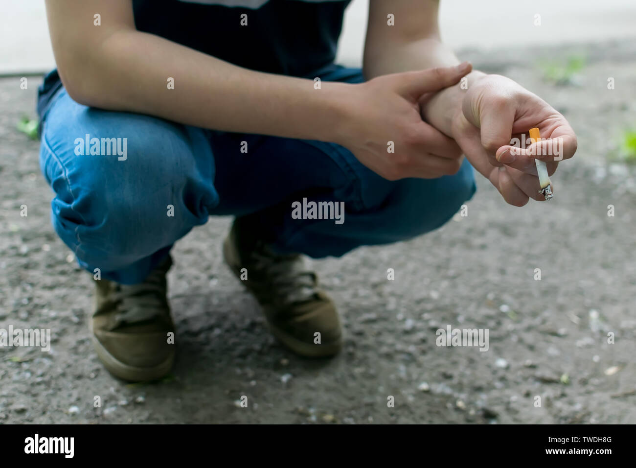 Feet of a man, a guy, close-up, which squatting and Smoking a cigarette ...