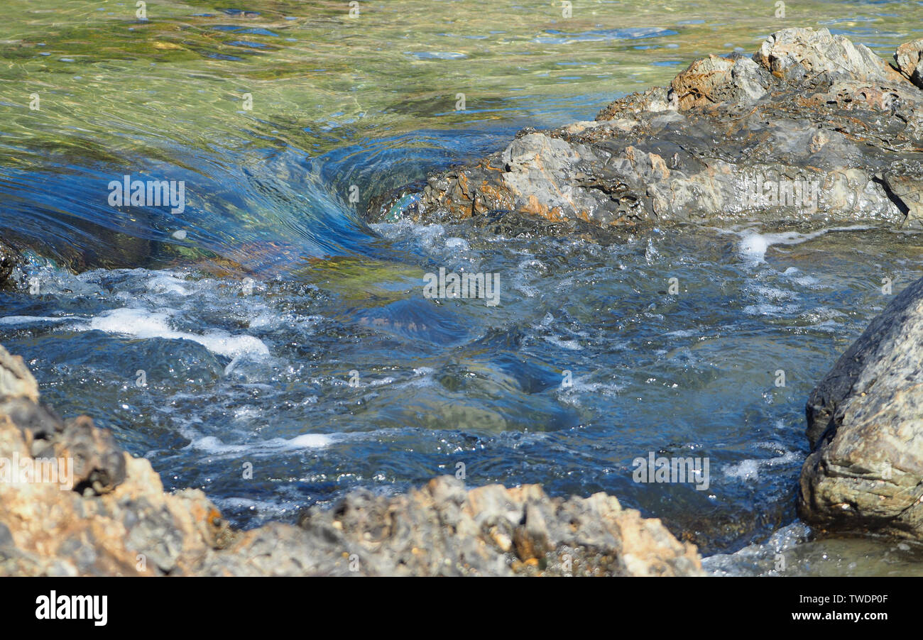 Salt water swirling around rocks in a coastal rock pool at the beach ...