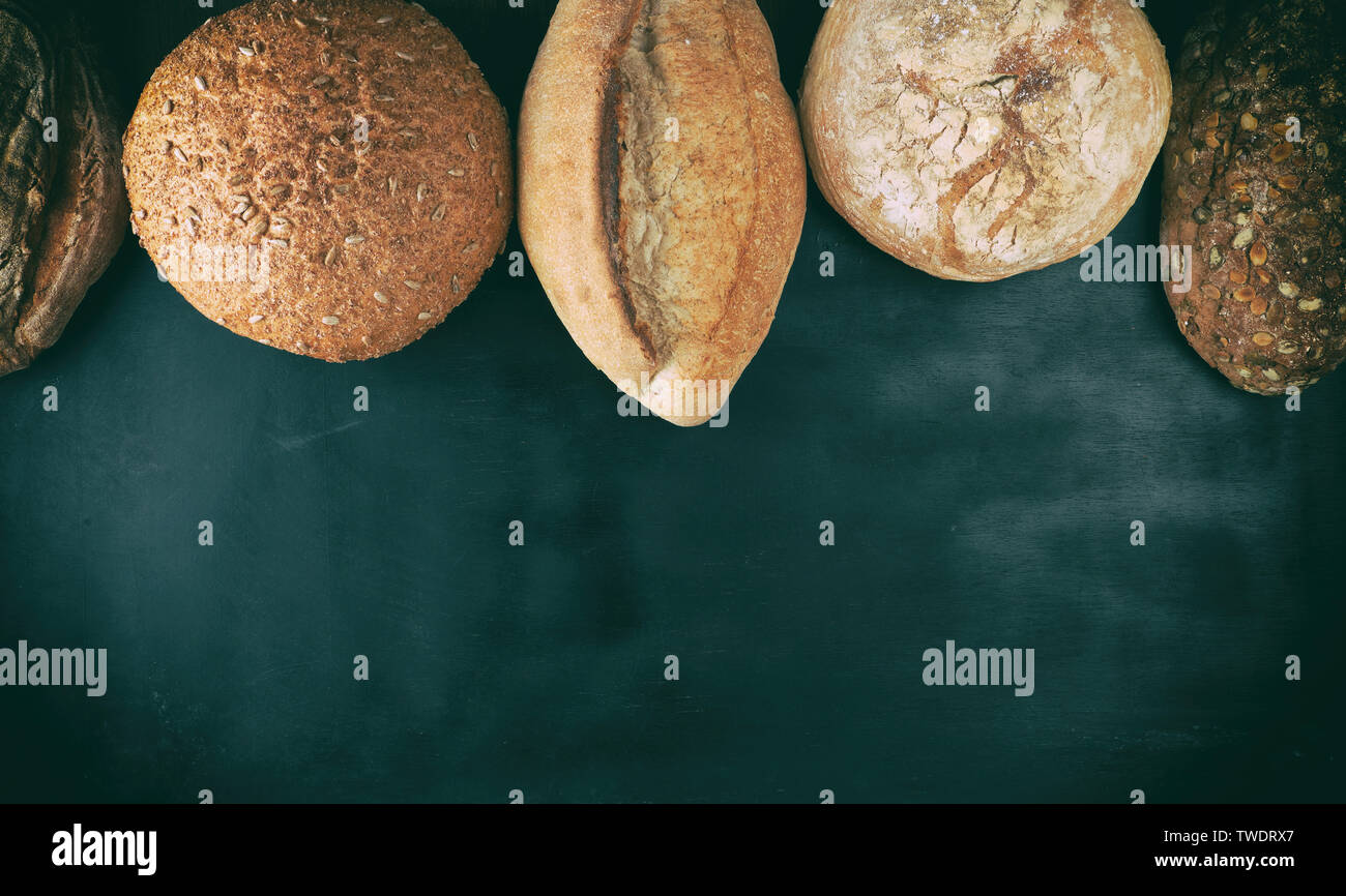 baked various loaves of bread on a black background, empty space , top ...