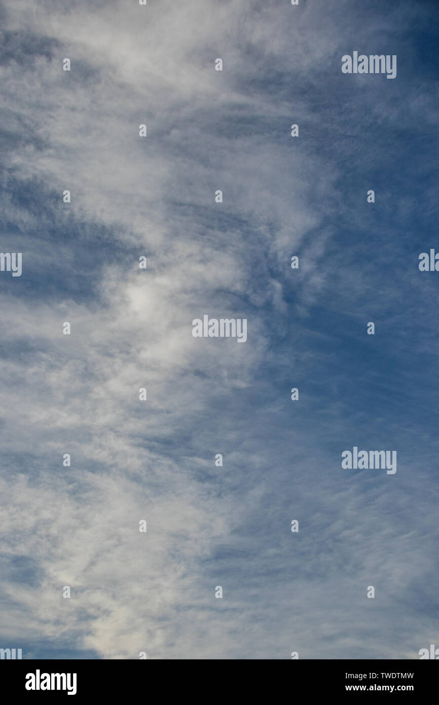 Wispy wind clouds isolated in a blue winter sky for background use ...