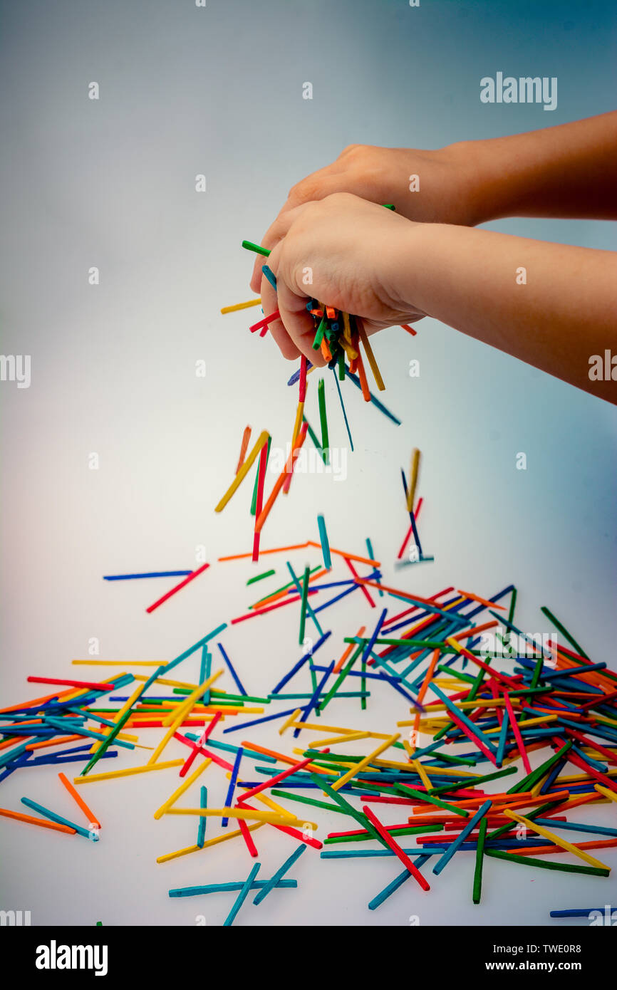 Hand letting coloured wooden sticks fall on white background Stock ...