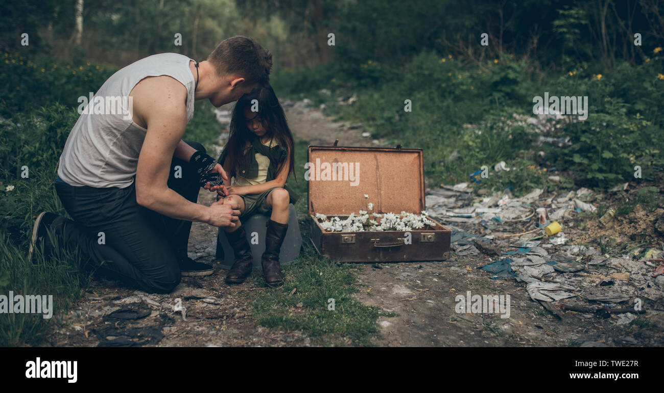 Homeless father and daughter are in garbage dump next to a suitcase ...