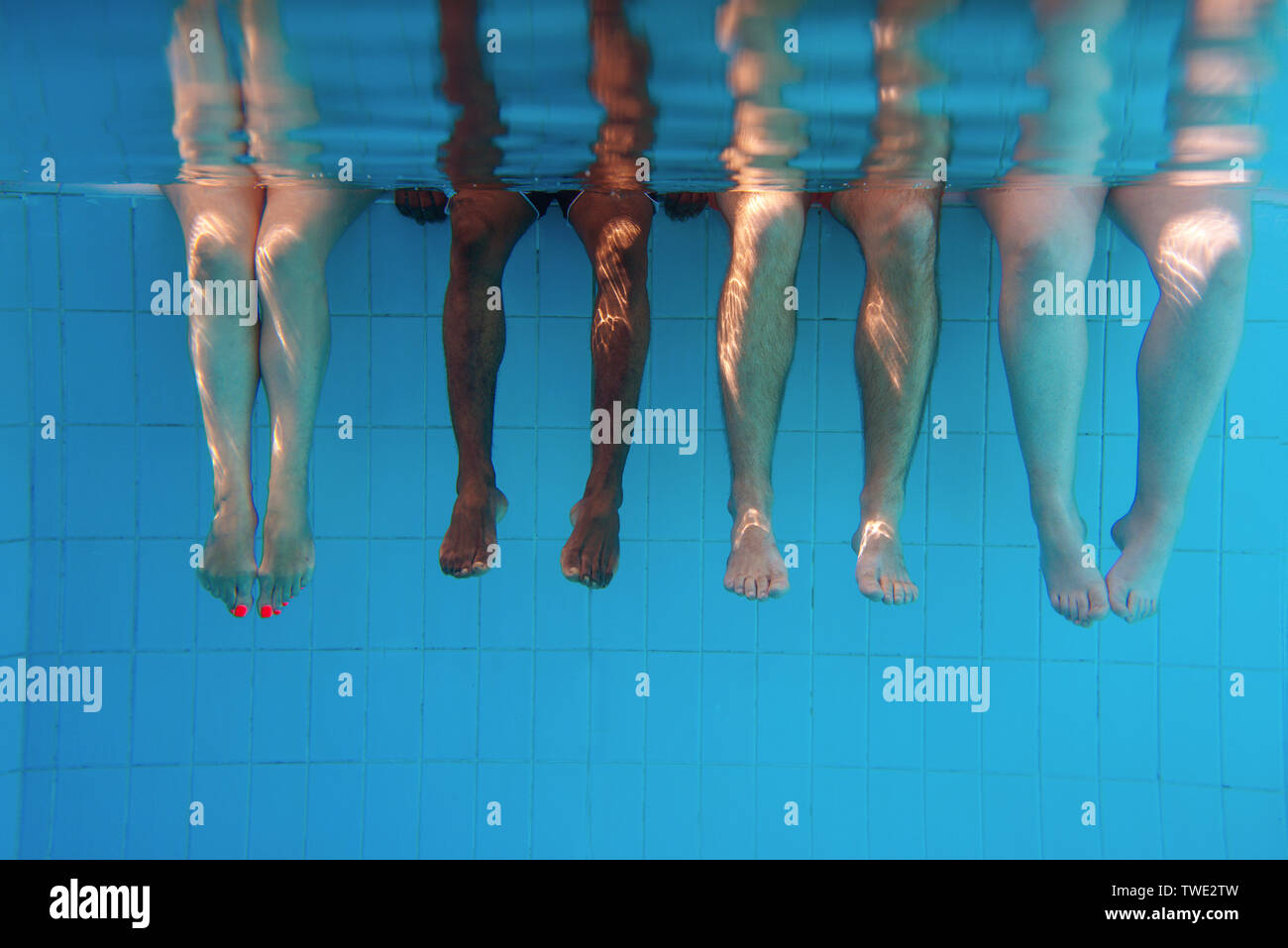 four people legs underwater in the swimming pool. Friends. Party ...