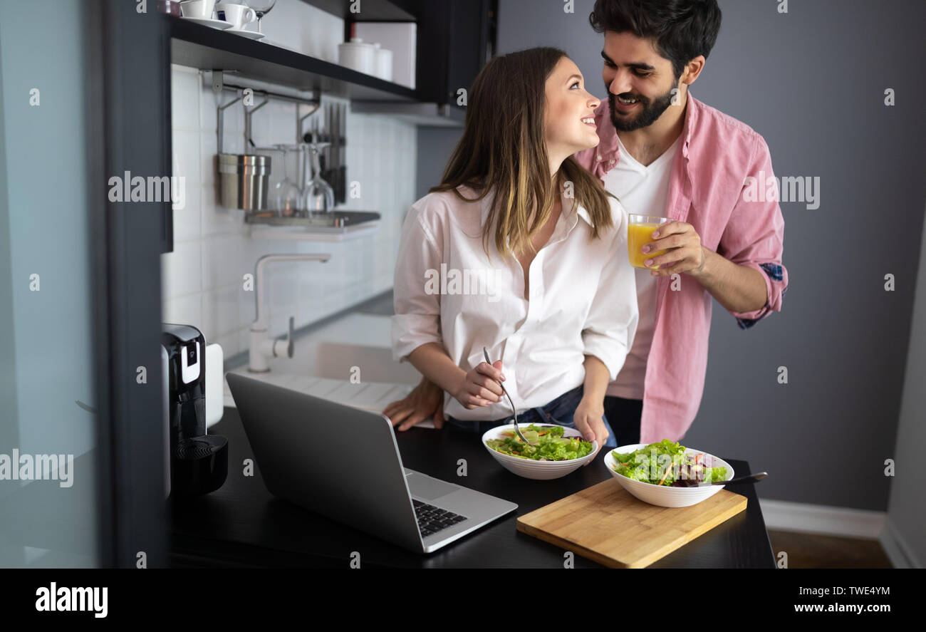 oung couple is talking and smiling while cooking healthy food in ...