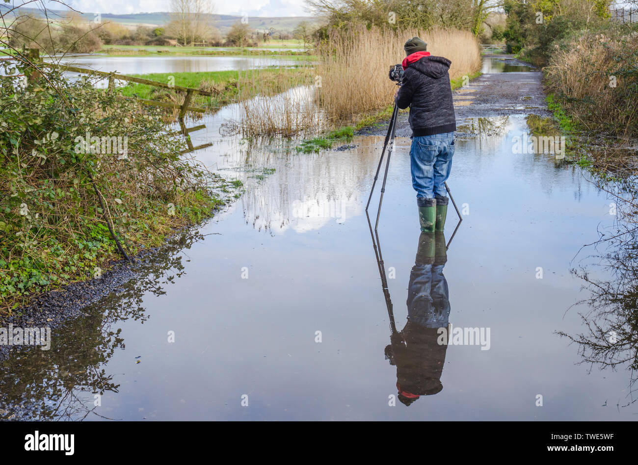 Photographer with camera on a tripod standing in a puddle with perfect ...