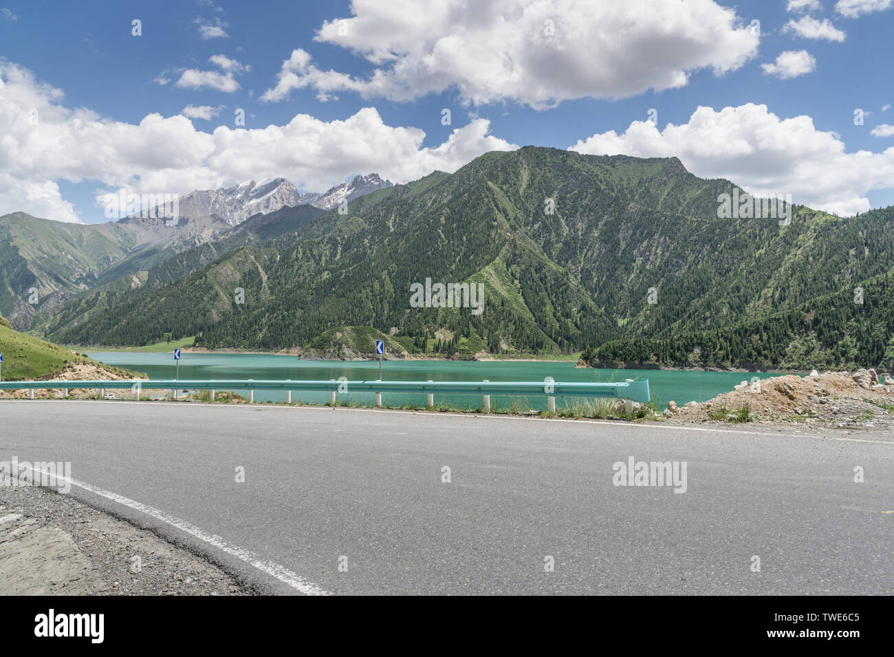 G217 Duku Highway bend in alpine forest under summer blue sky and white ...