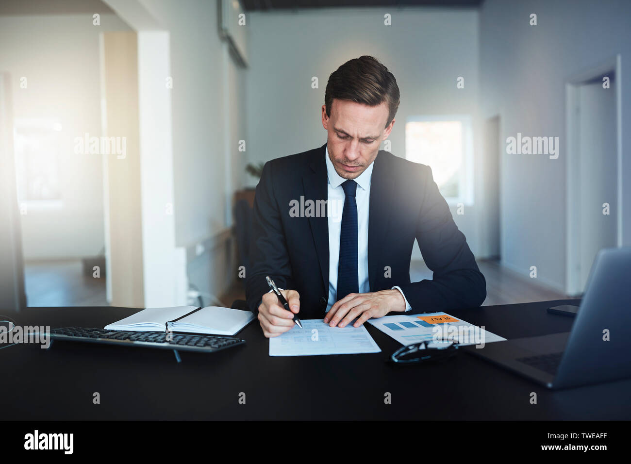 Focused businessman going over paperwork and signing documents while ...