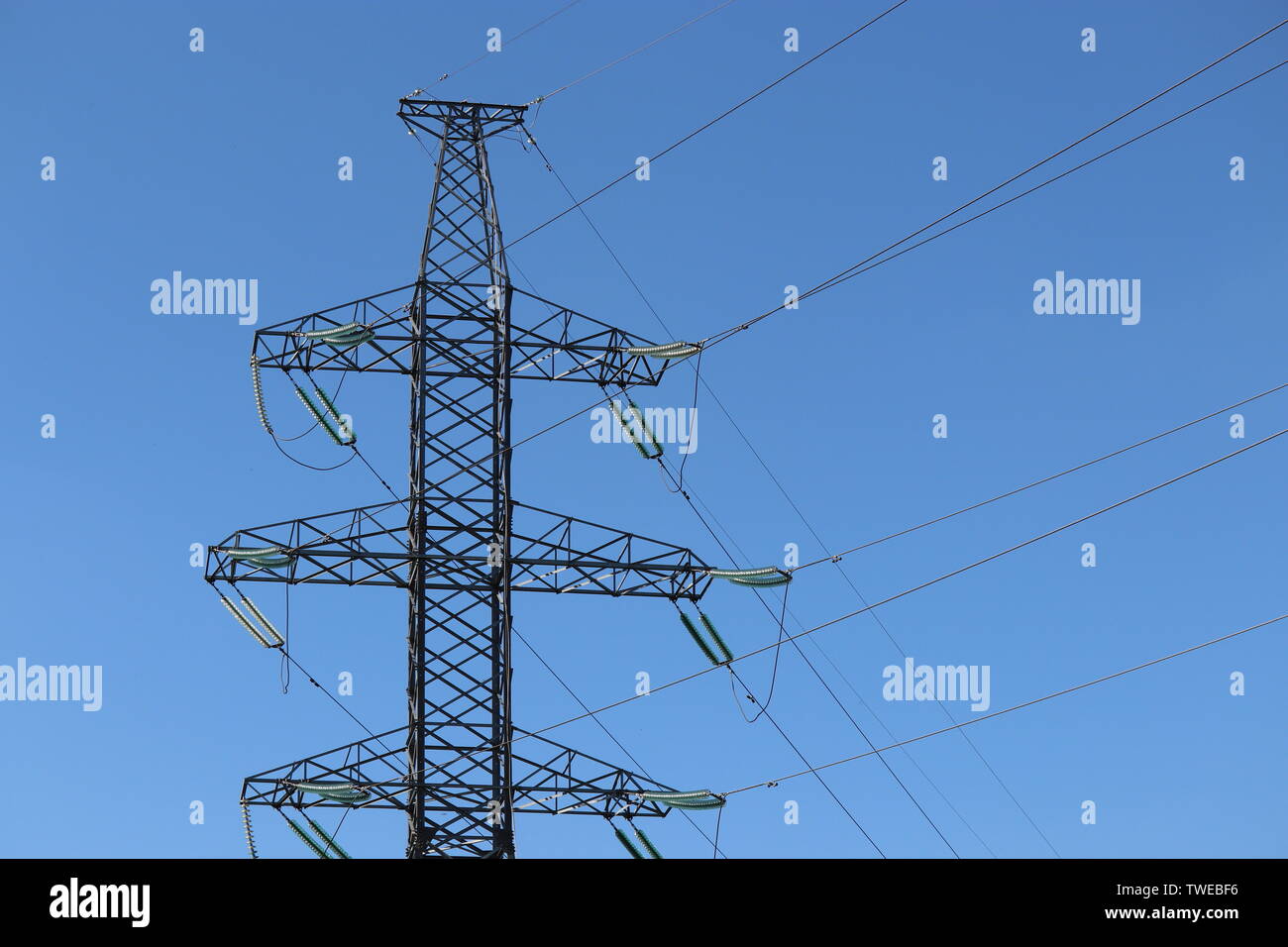 High voltage power line supports with electrical wires isolated on blue ...
